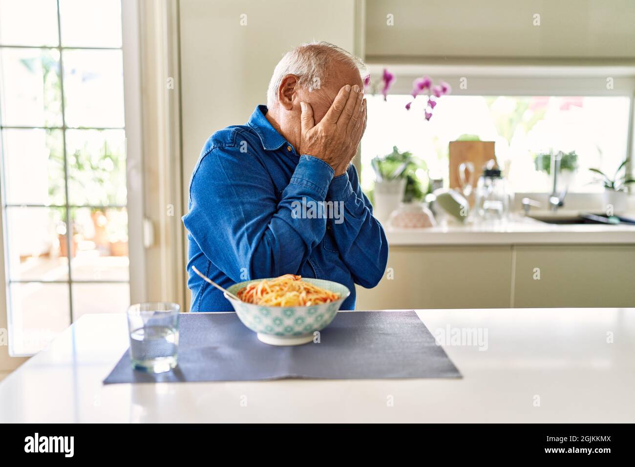 Senior man with grey hair eating pasta spaghetti at home with sad ...