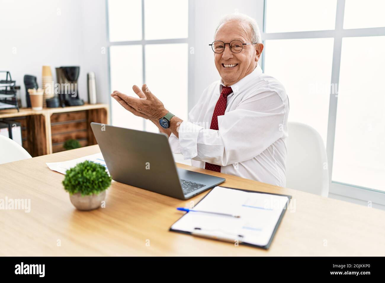 Senior man working at the office using computer laptop pointing aside ...