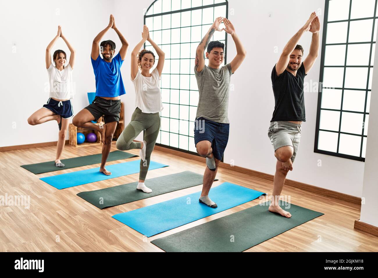 Group of young sporty people smiling happy training yoga at sport ...