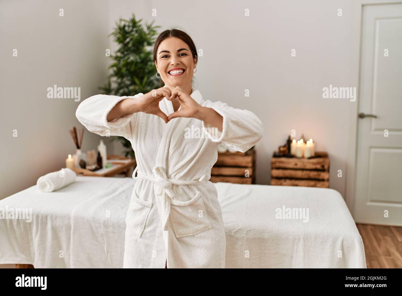 Young beautiful hispanic woman wearing bathrobe at wellness spa smiling ...