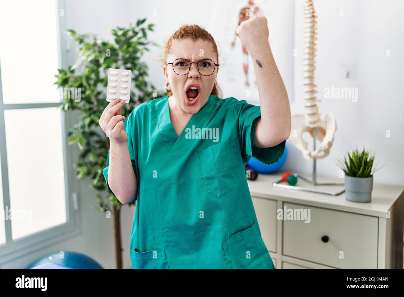 Young redhead physiotherapist woman holding prescription pills annoyed ...