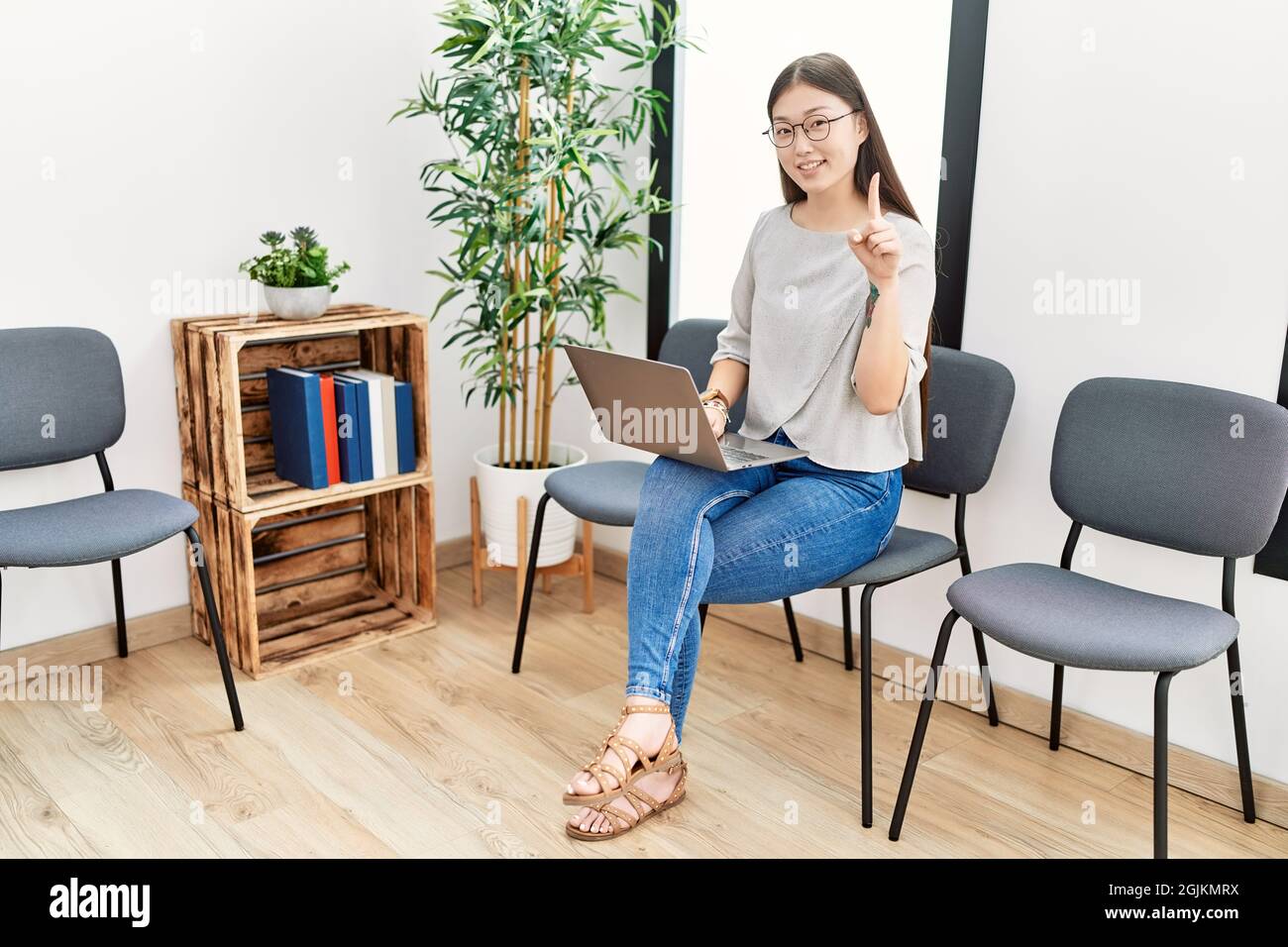 Young asian nurse woman sitting at waiting room using laptop surprised ...