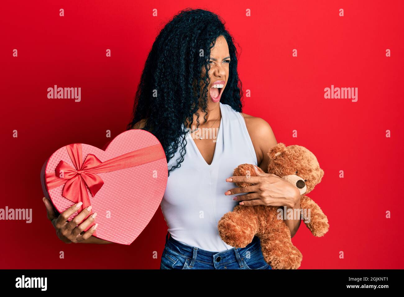 Middle age african american woman holding valentine gift angry and mad ...