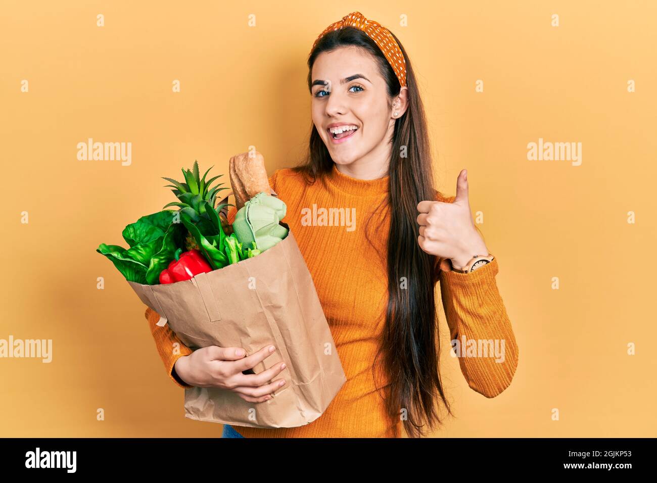 Young brunette teenager holding paper bag with groceries feeling unwell ...