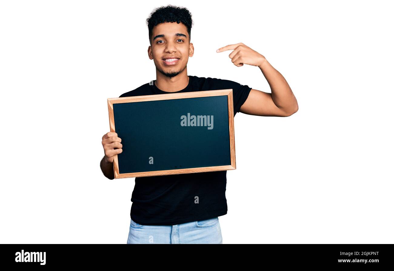 Young african american man holding blackboard pointing finger to one ...
