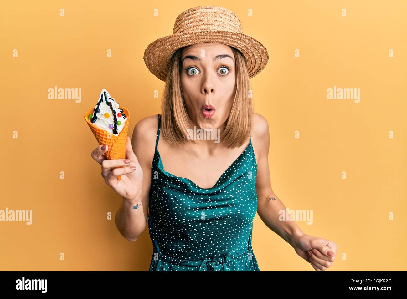 Young caucasian blonde woman eating ice cream scared and amazed with ...