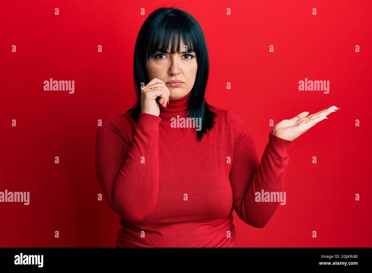 Young hispanic woman presenting with open palms, holding something ...