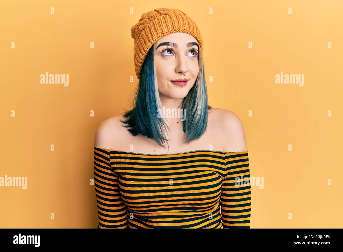 Young modern girl wearing wool hat smiling looking to the side and ...