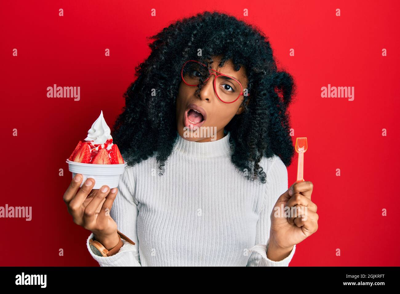 African american woman with afro hair eating strawberry ice cream in ...