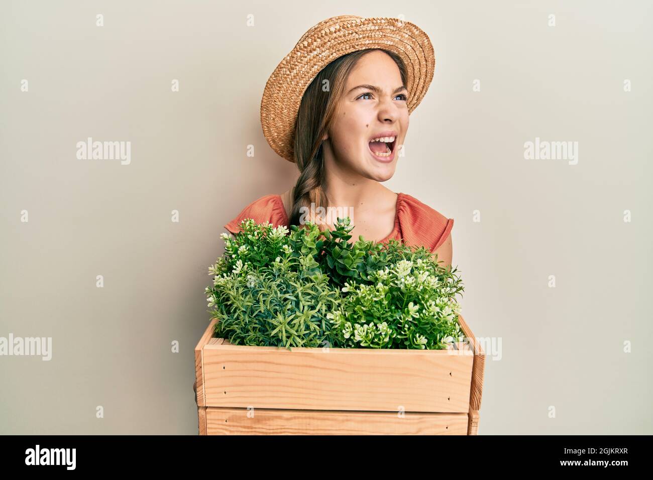 Beautiful brunette little girl wearing gardener hat holding wooden ...