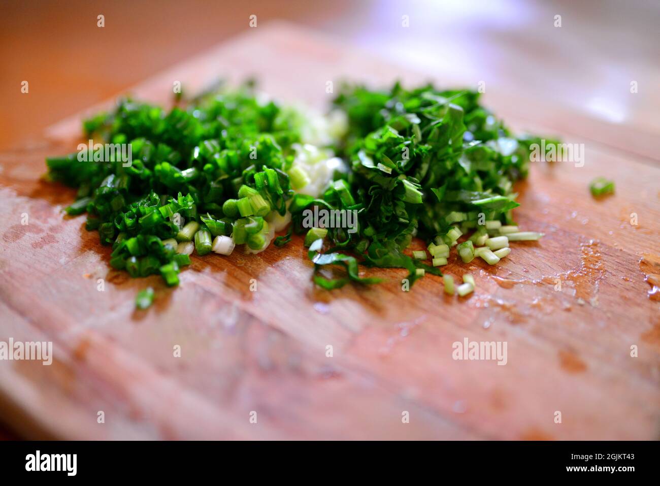 Chopped wild garlic and scallions on wooden kitchen board Stock Photo ...