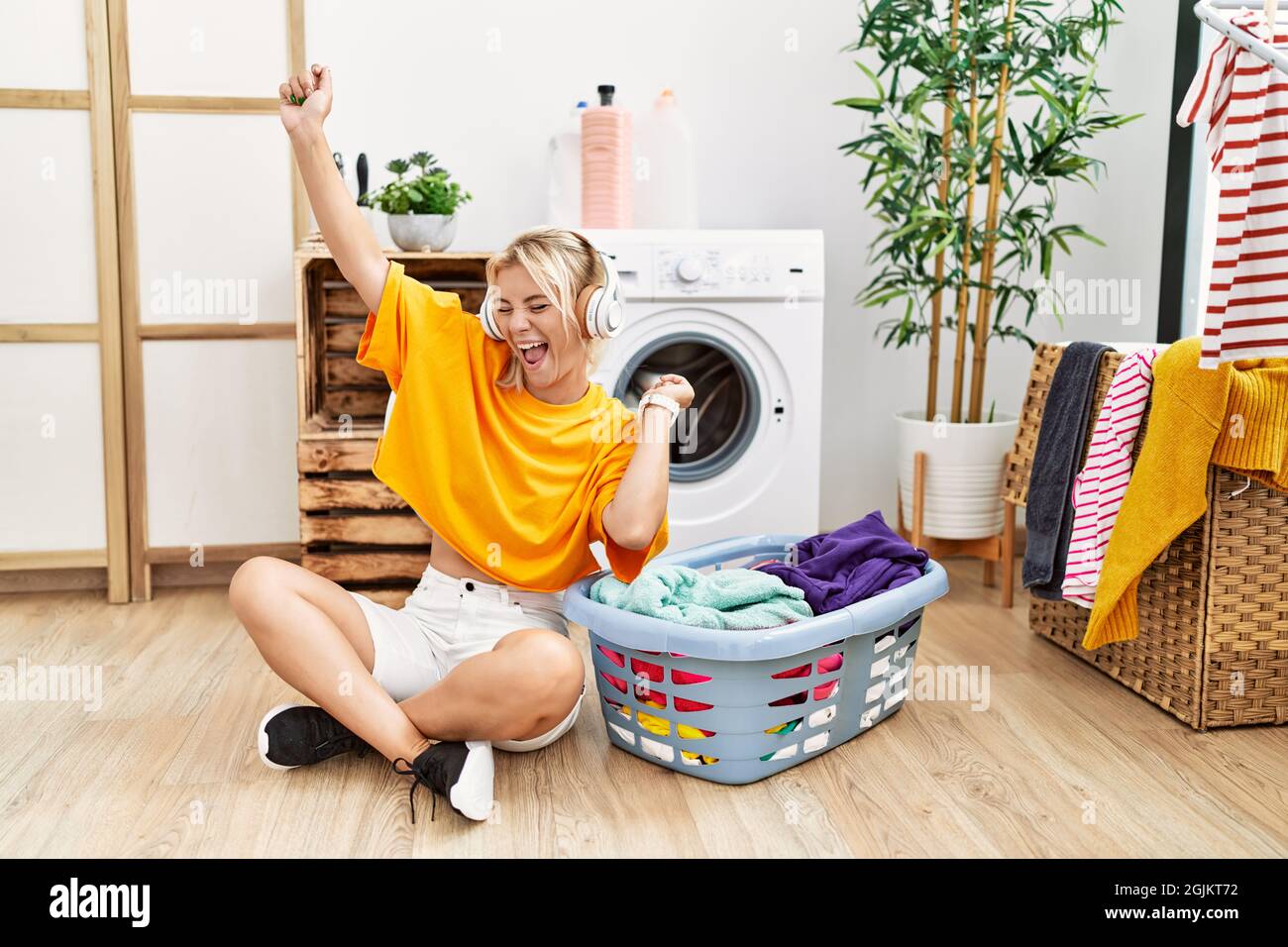Young blonde girl doing laundry listening to music at home Stock Photo ...
