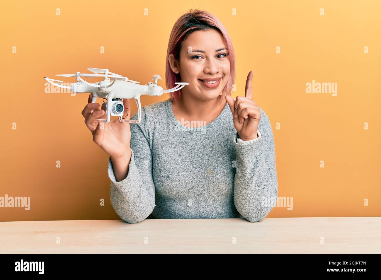 Hispanic woman with pink hair using drone smiling with an idea or ...