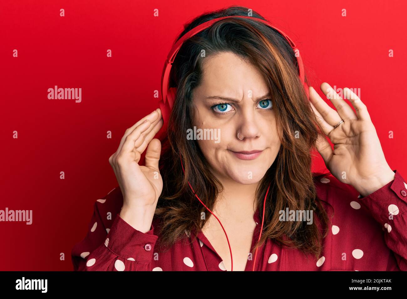 Young caucasian woman listening to music using headphones skeptic and ...
