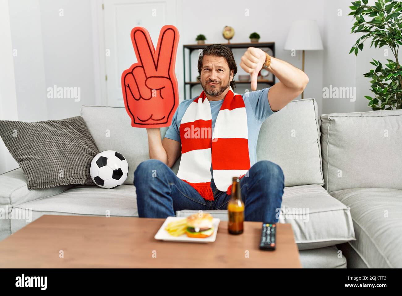 Handsome middle age man football hooligan cheering game at home with ...