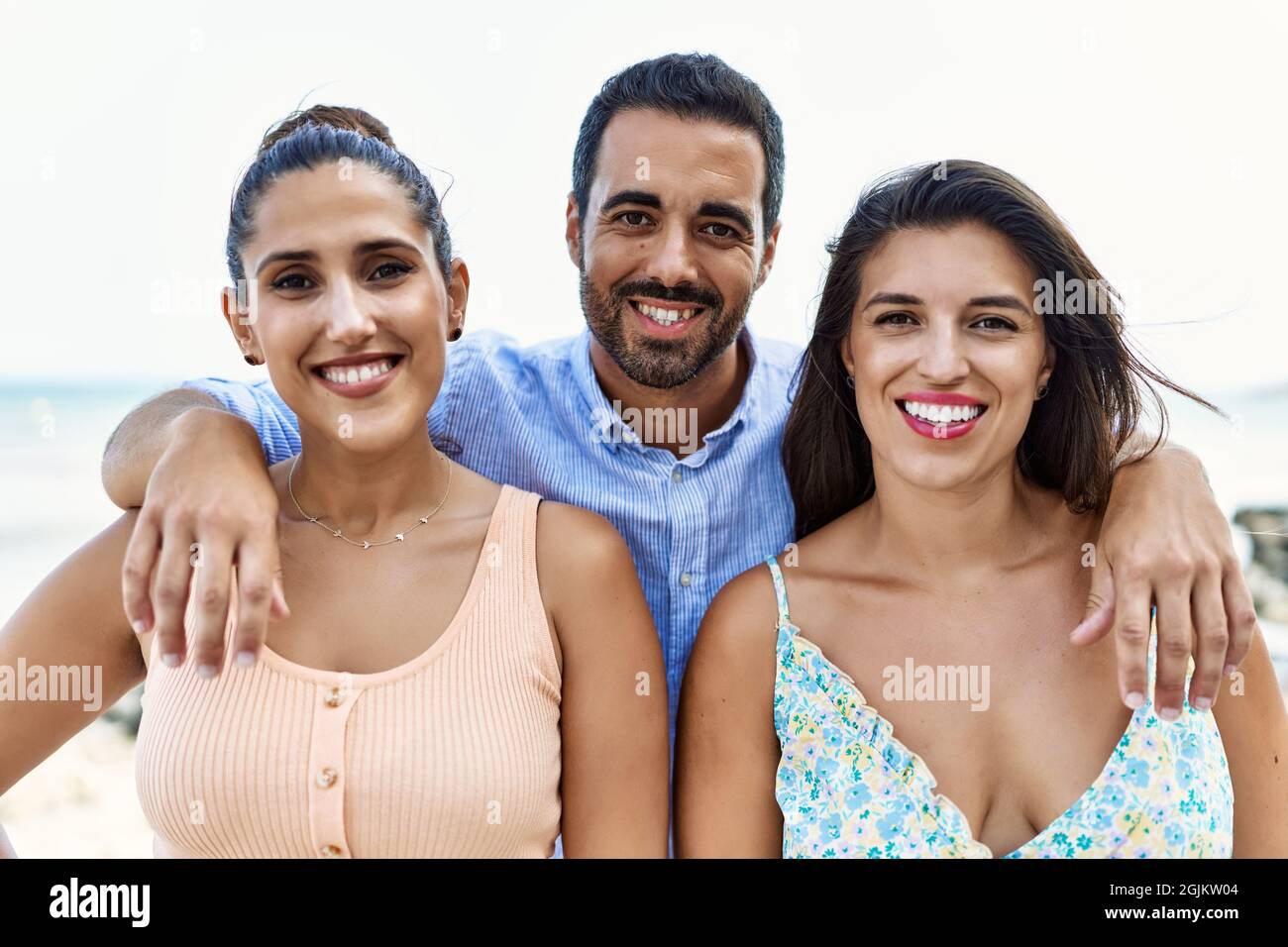 Three young hispanic friends smiling happy and hugging at the beach ...