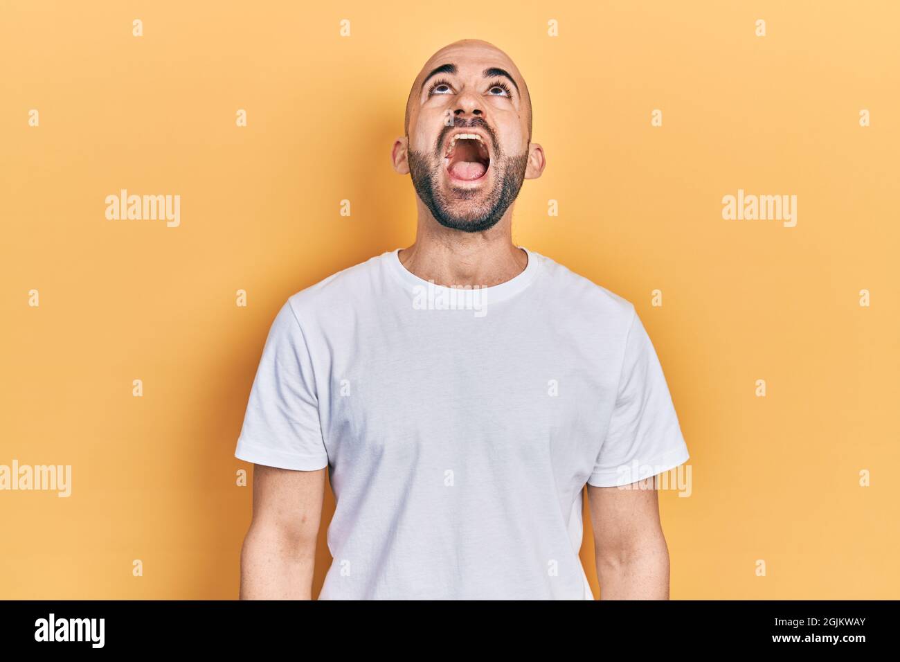 Young bald man wearing casual white t shirt angry and mad screaming ...