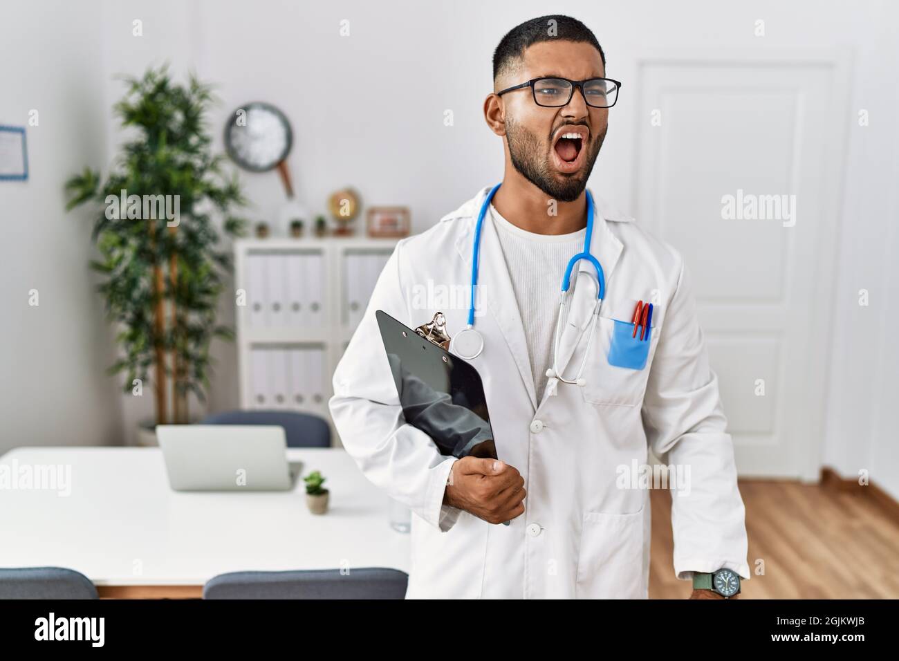 Young indian man wearing doctor uniform and stethoscope angry and mad ...