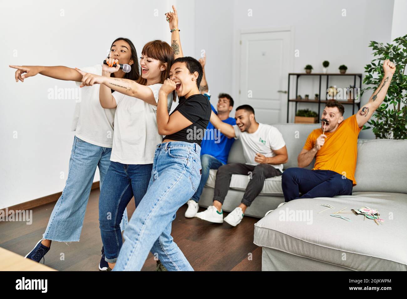 Group of young friends having party singing song using microphone at ...
