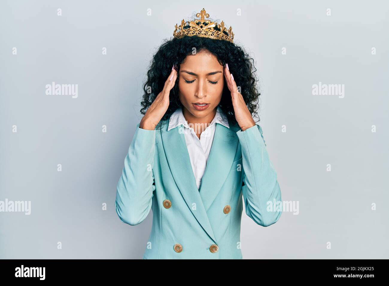 Young latin girl wearing business clothes and queen crown suffering ...