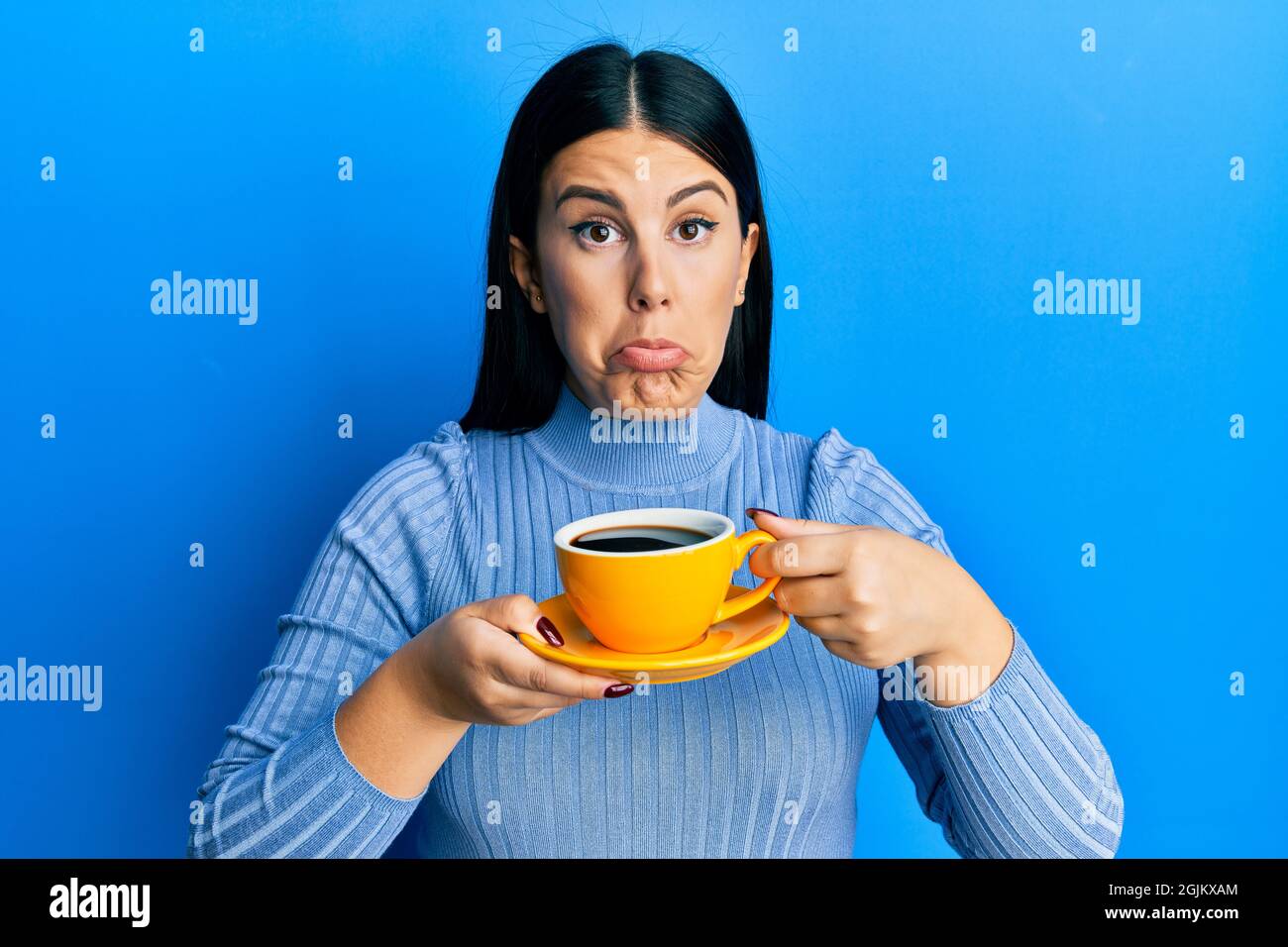 Beautiful brunette woman drinking a yellow cup of black coffee ...