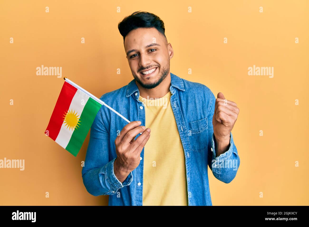 Young arab man holding kurdistan flag screaming proud, celebrating ...