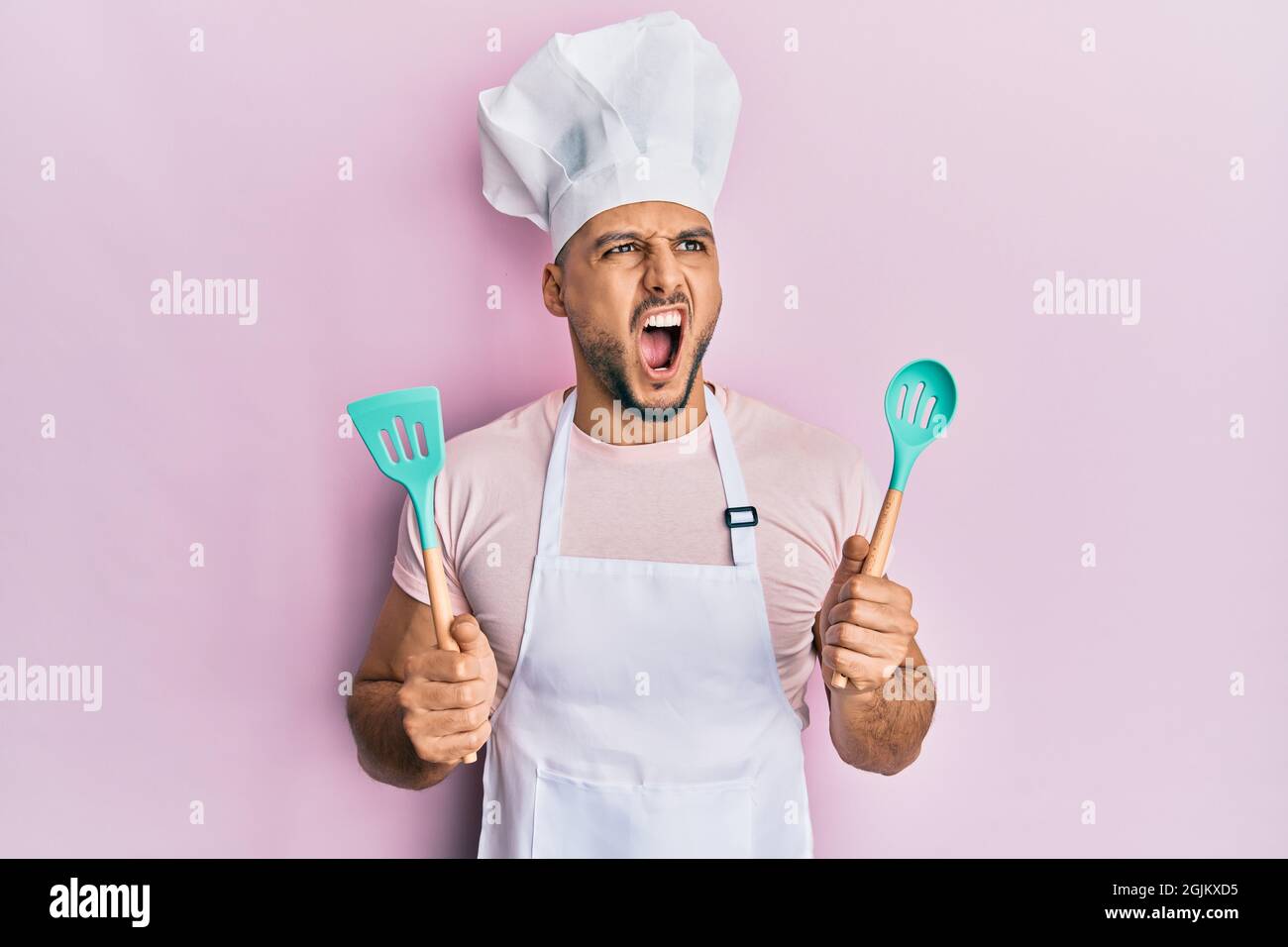 Young arab man wearing professional cook apron and hat holding spoon ...