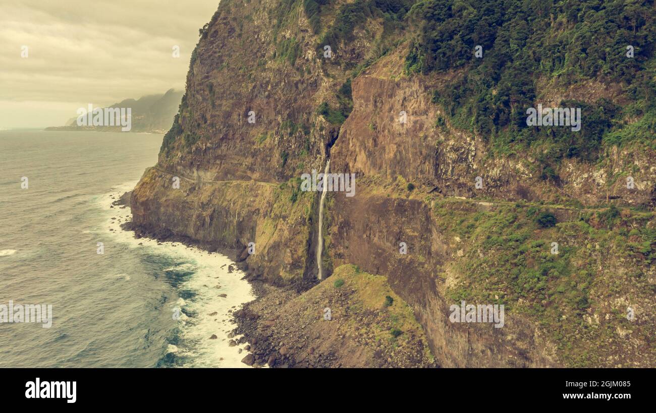 Waterfall falling into ocean from volcanic cliffs Stock Photo - Alamy