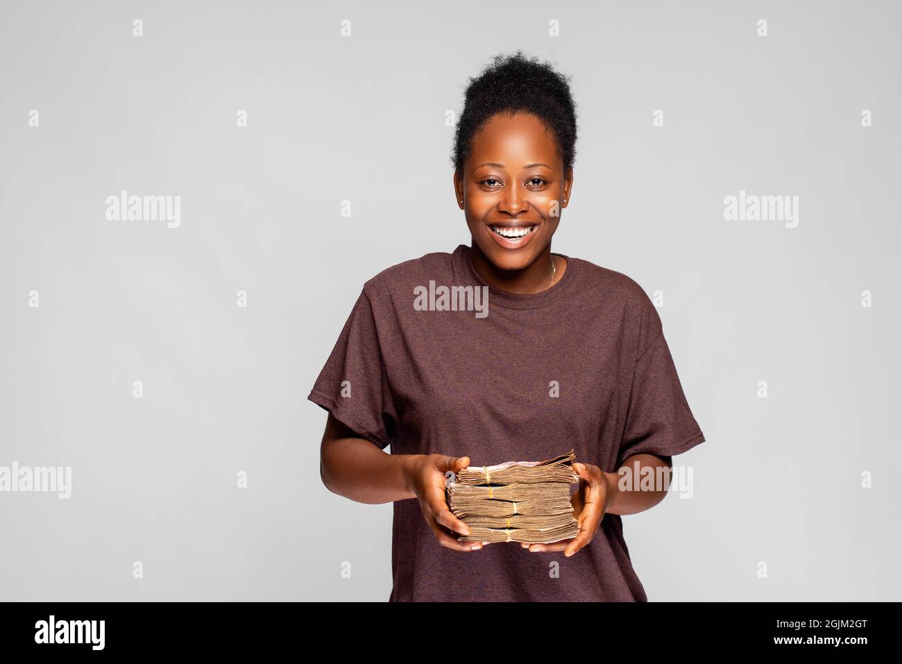 young nigerian woman holding a lot of cash feeling happy with a smile ...