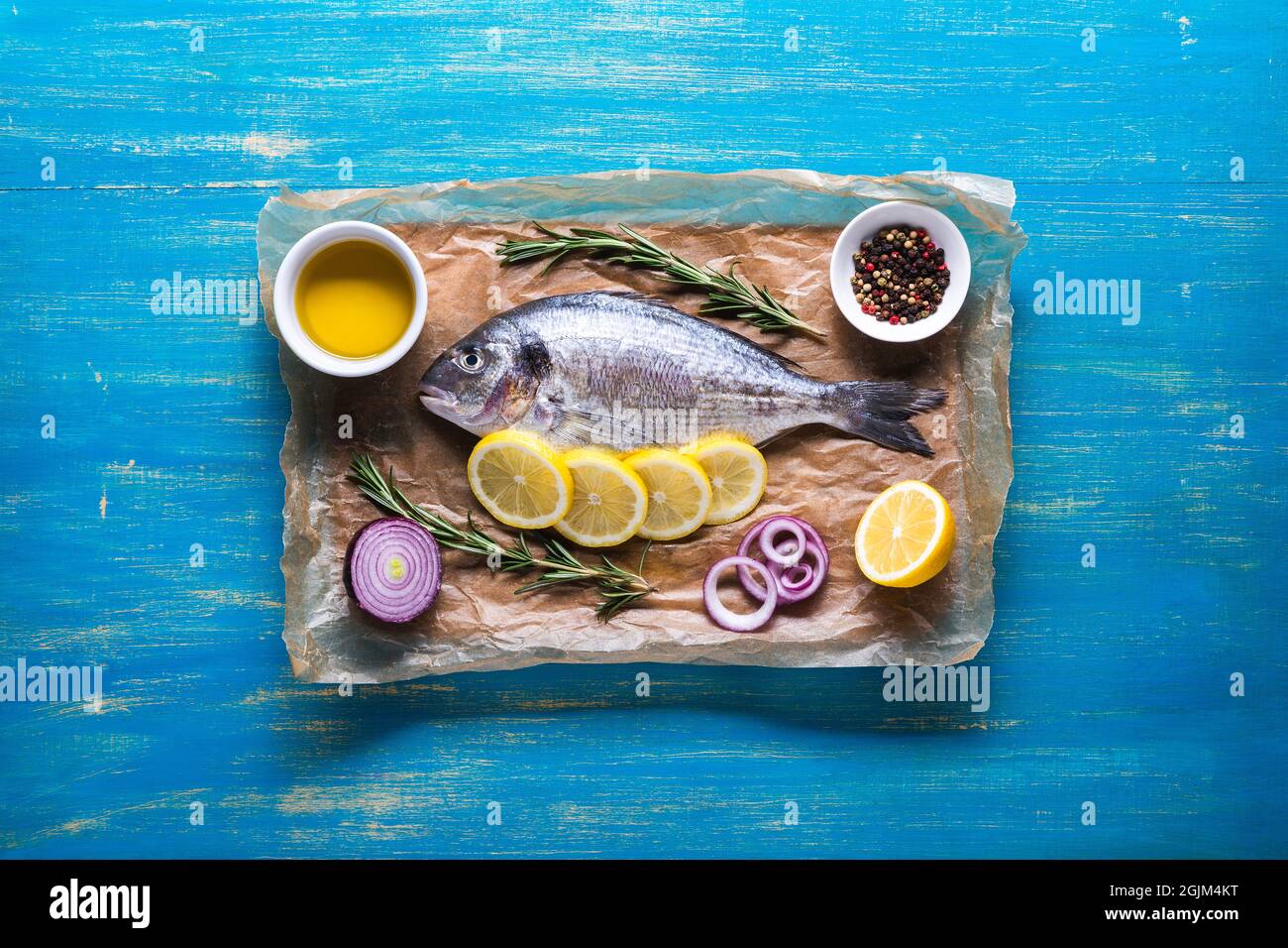 Dorado fish prepared for cooking on a cutting board and and parchment ...