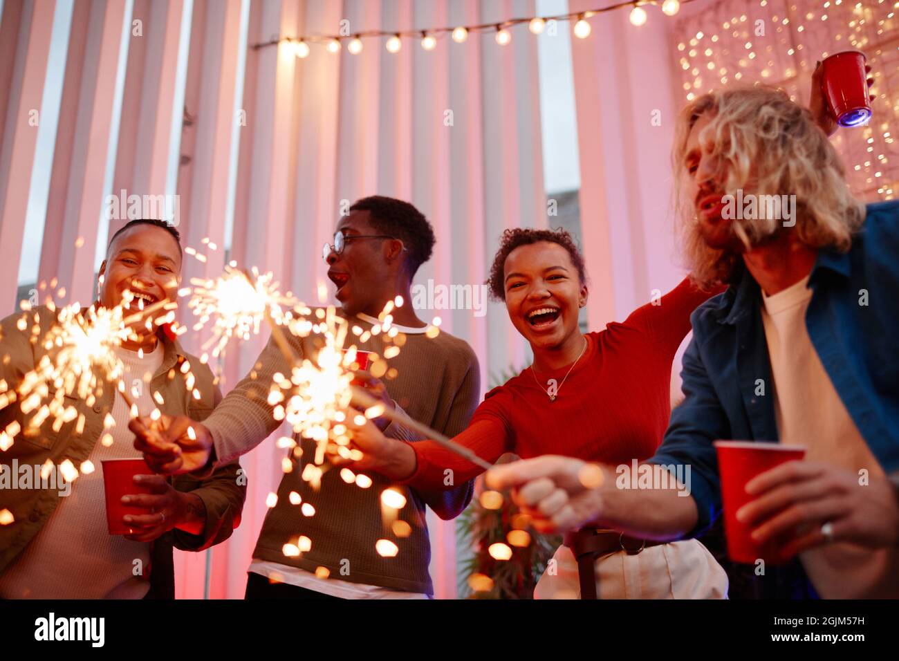 Waist up portrait of diverse group of friends holding light while ...
