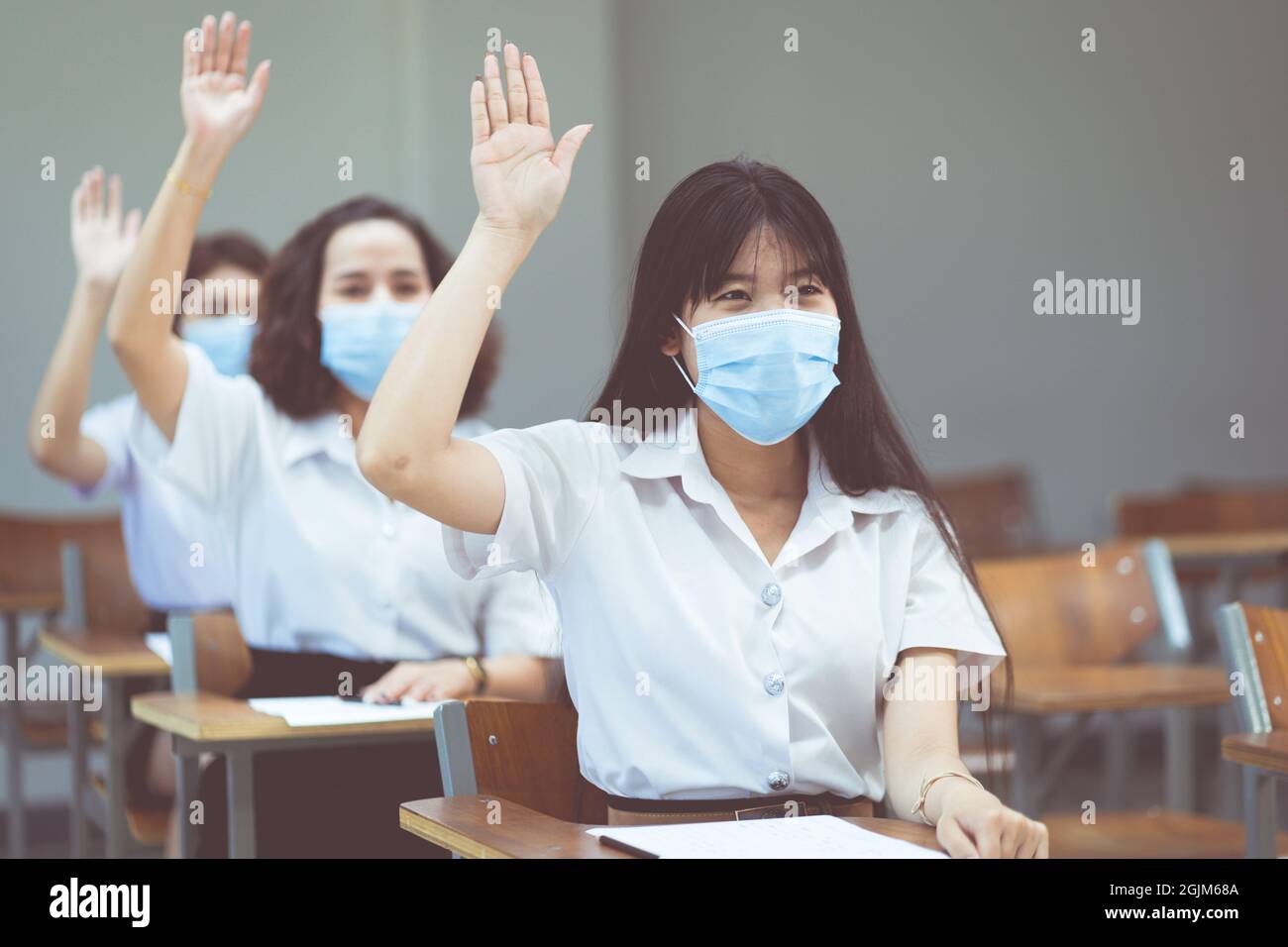 Group of Asian female college students in covid masks raising their ...