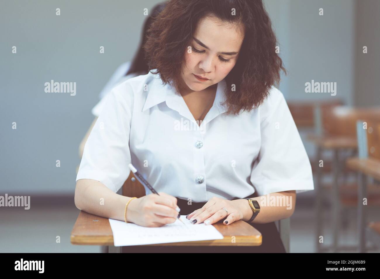 Asian female college student taking notes while studying in a classroom ...