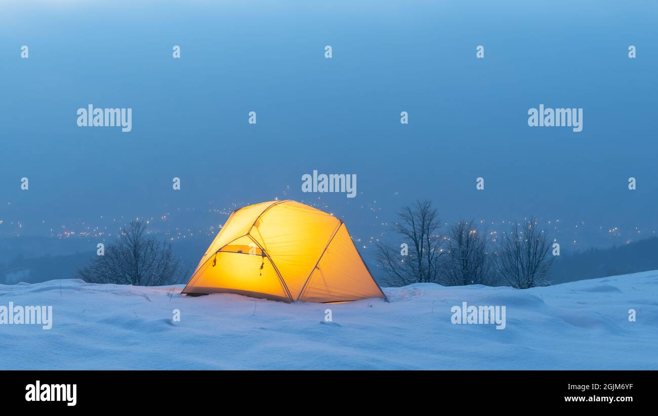 Yellow tent lighted from the inside against the backdrop of glowing ...