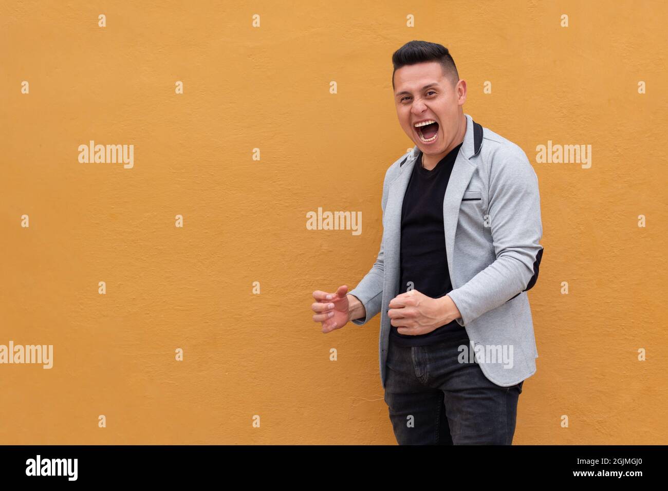 Man against yellow wall. Man giving a victory shout with his body ...