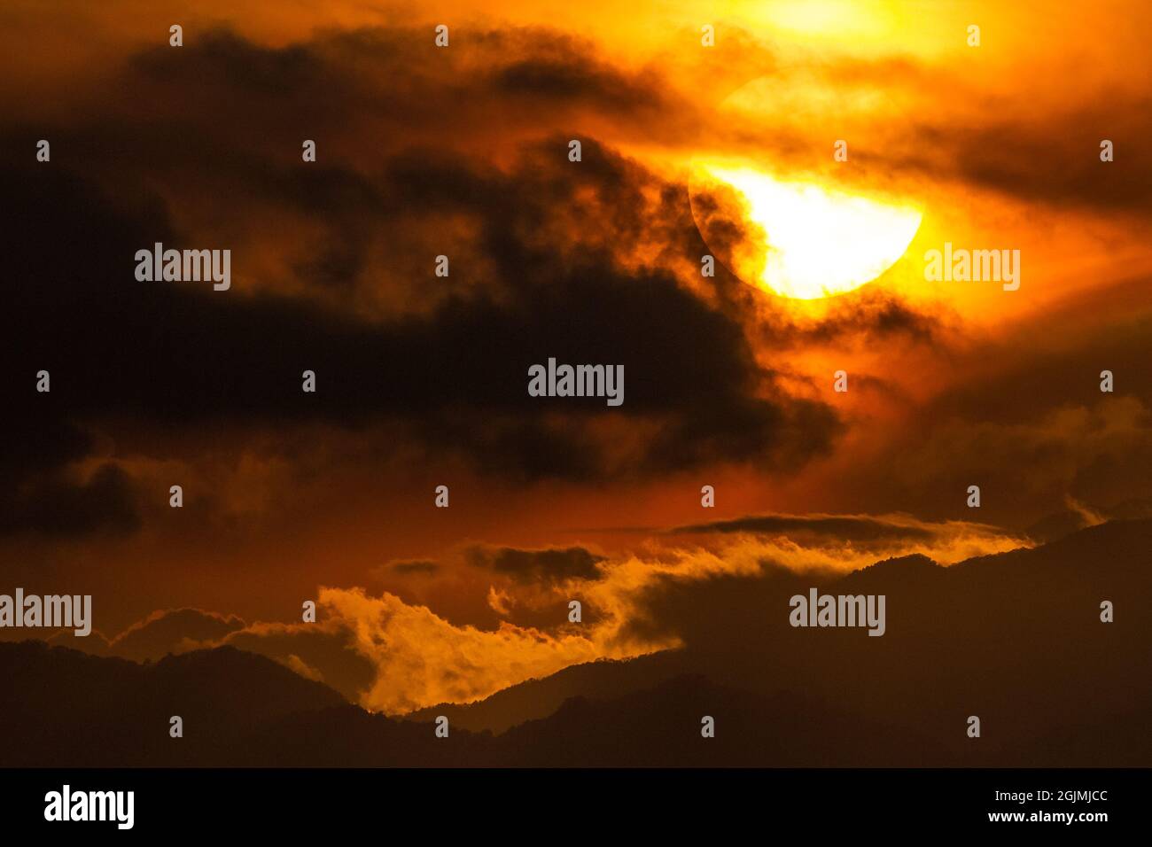 The disk of the sun at sunset in dramatic clouds over mountains in Japan Stock Photo - Alamy