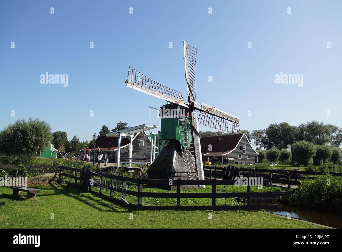 Walking tourists over a small drawbridge and a small windmill in the ...