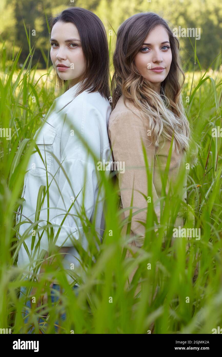 Two young women brunette and blonde are standing in a field. Romantic ...
