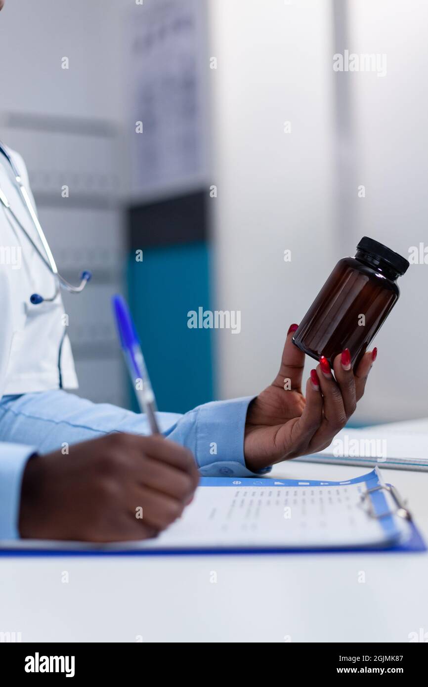 Close up of african american hand holding bottle of medicine on white ...