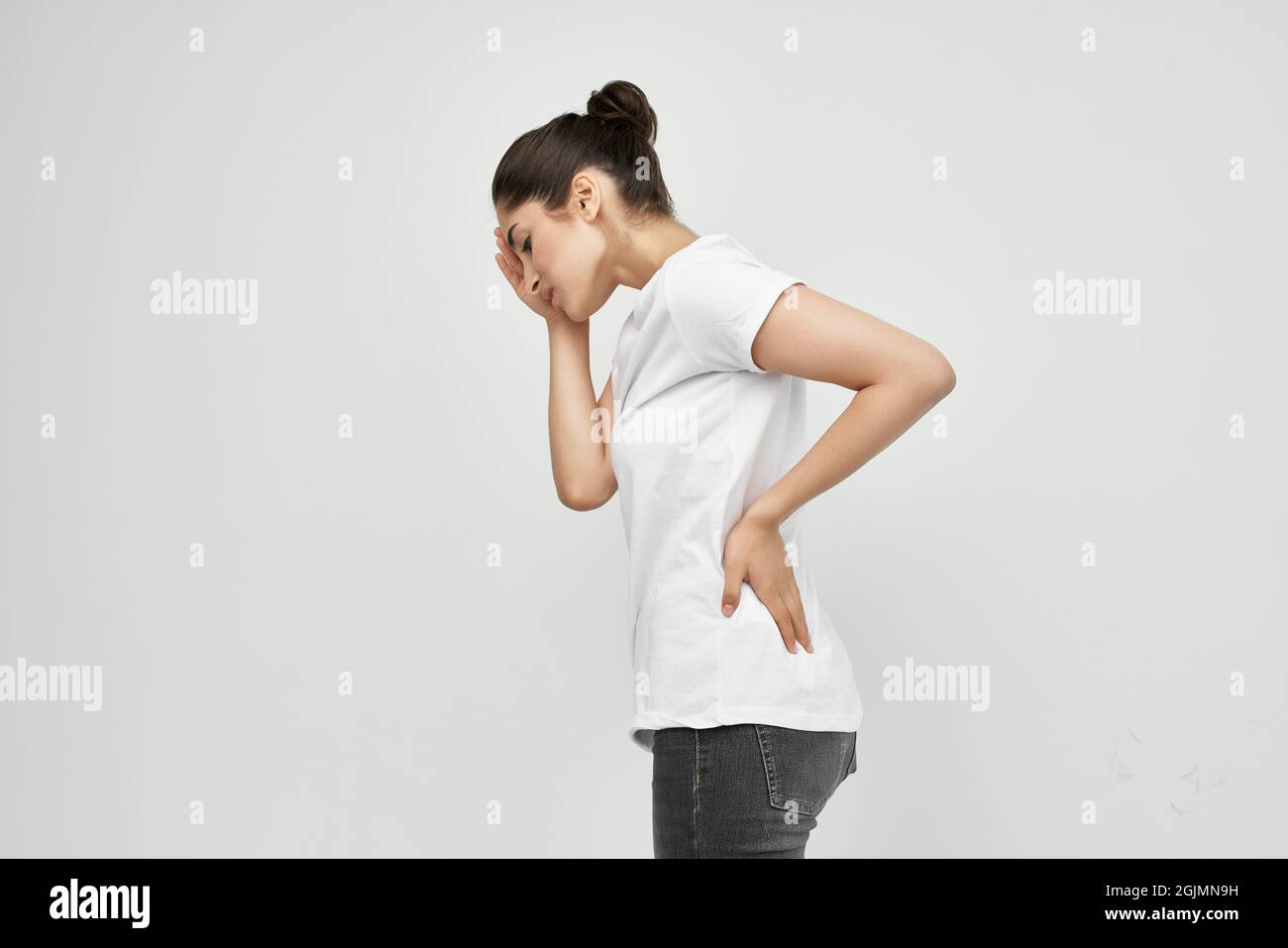 woman in white t-shirt holding her lower back health problems Stock ...