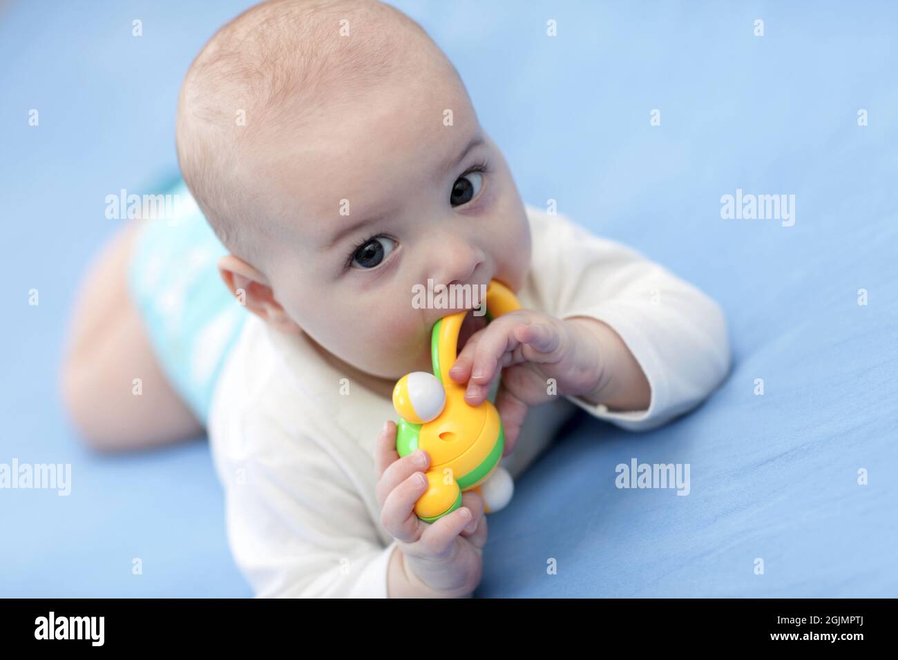The baby boy with a rattle on a blue sheet Stock Photo - Alamy