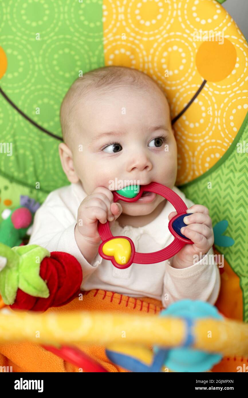 The baby boy biting a rattle ring at home Stock Photo - Alamy