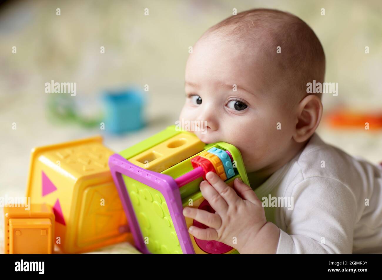 The boy biting a toy on a bed at home Stock Photo - Alamy