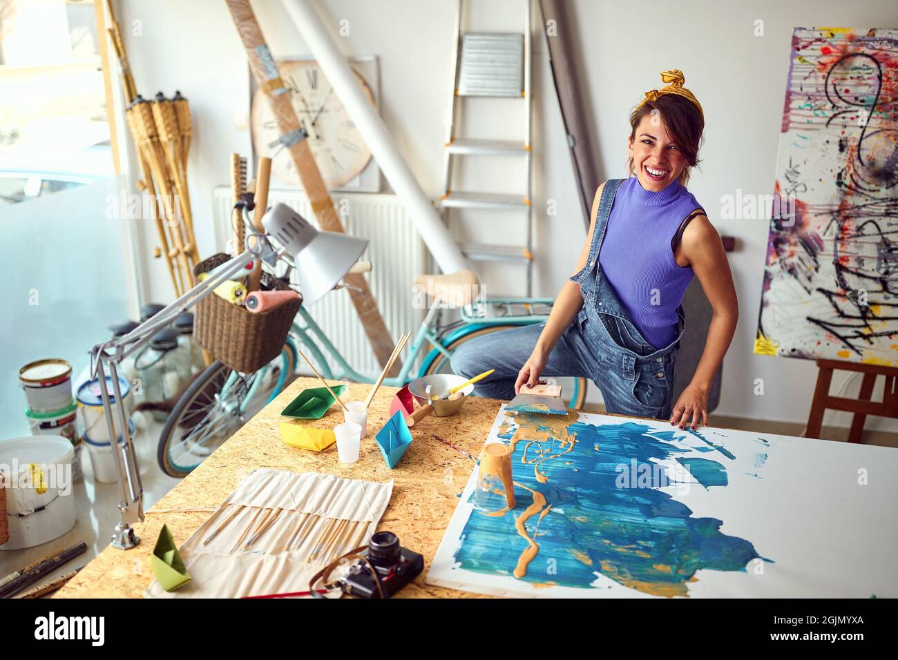 A young female artist is posing while working on a new painting in a ...