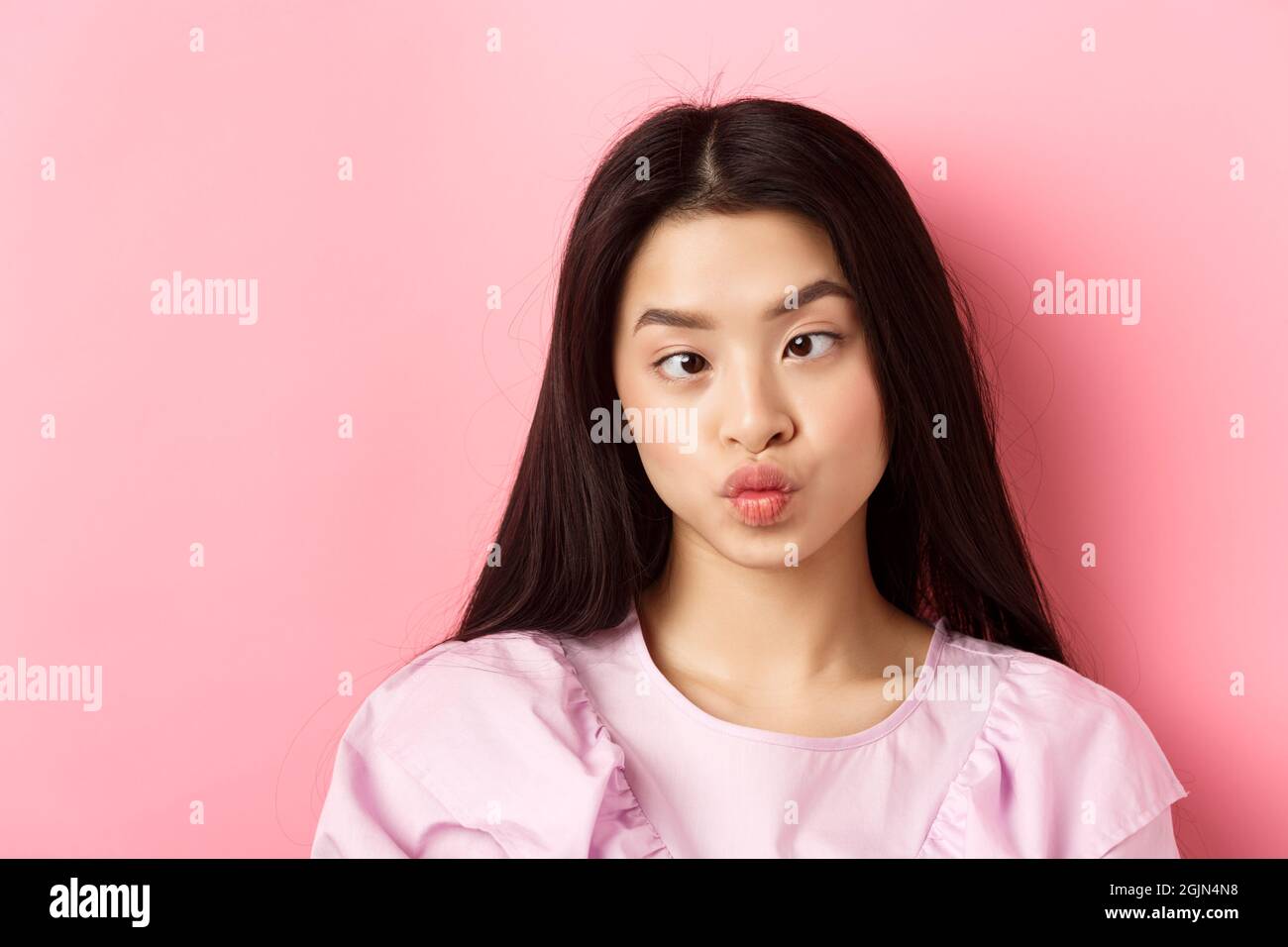 Close-up portrait of funny asian woman squinting eyes and making silly ...