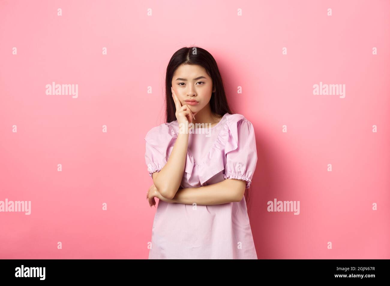 Bored asian teen girl look indifferent at camera, lean face on hand in ...