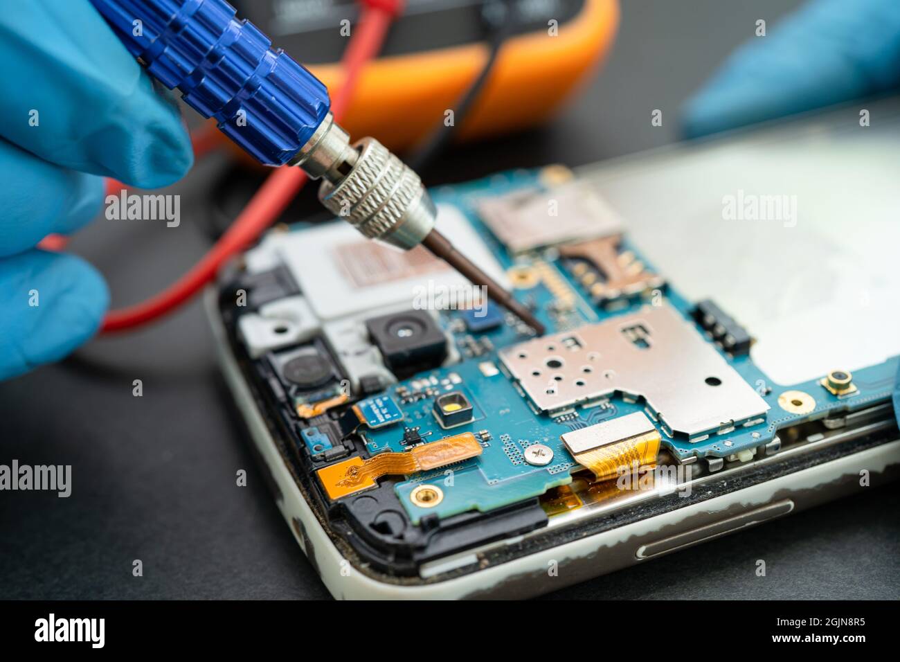 Technician repairing inside of mobile phone by soldering iron ...