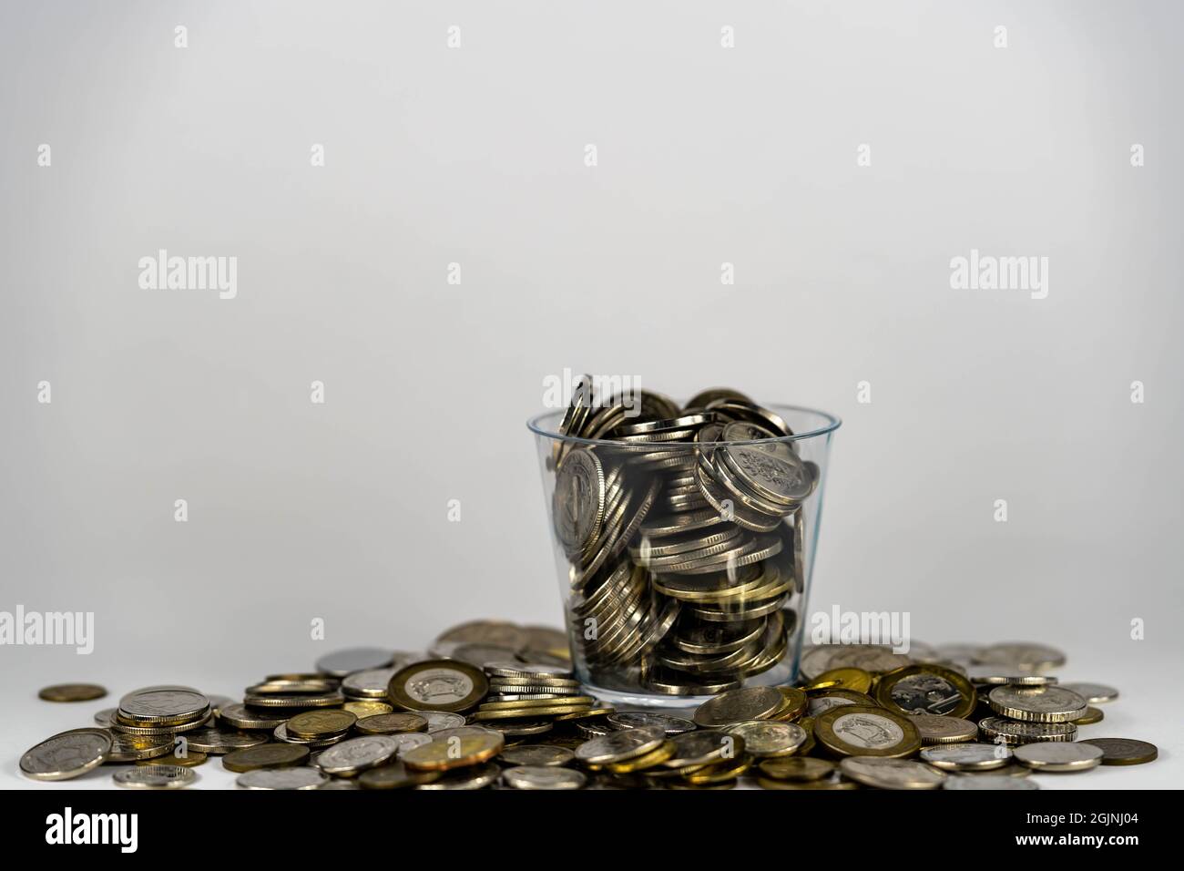 Coins inside a plastic container. Coins scattered on white background ...
