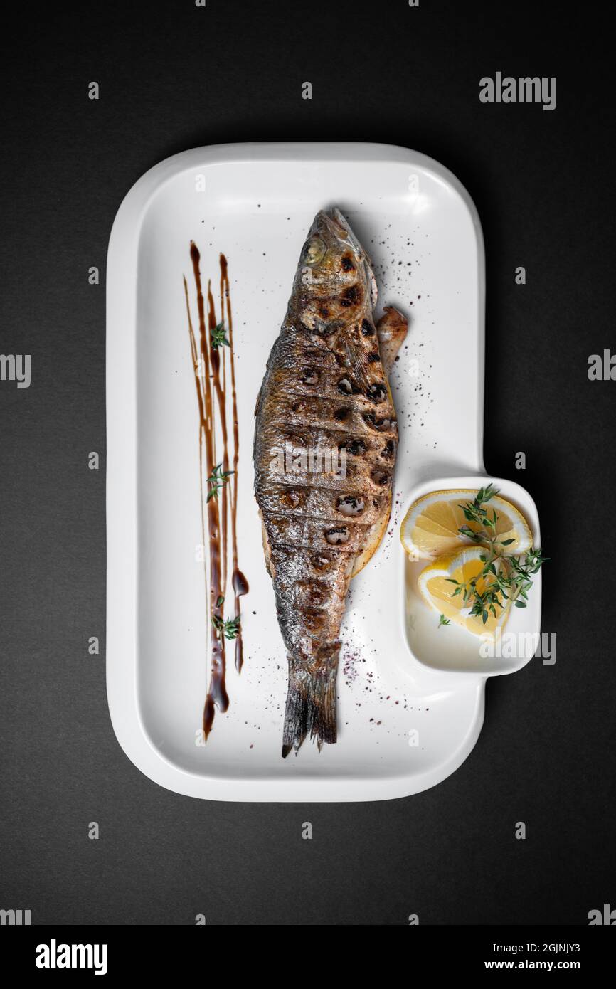 close up of whole grilled stuffed fish sea bass with lemon on black ...