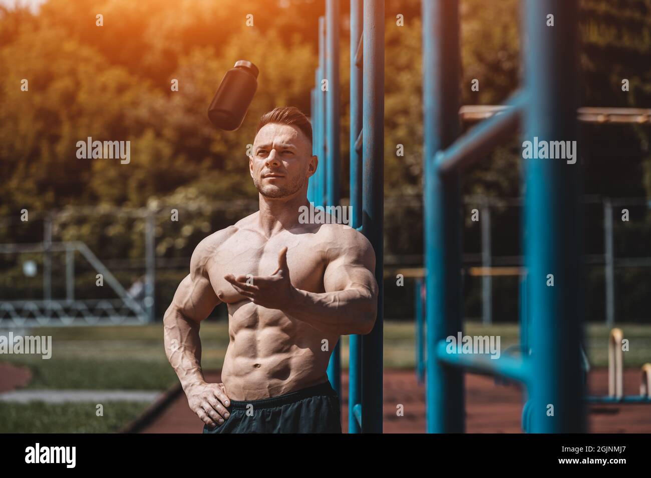 muscular athlete man throw up black container with protein whey powder ...